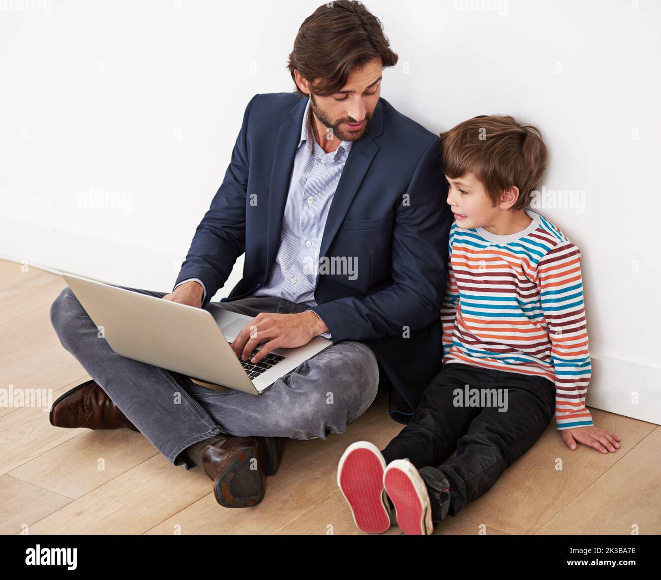 Technology brings them together. A father and son sitting on the floor ...