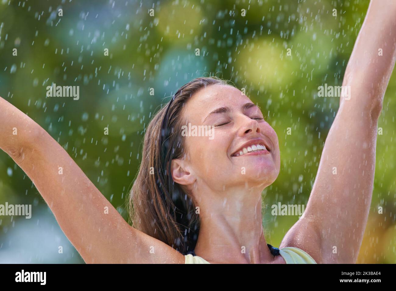 The rain makes me feel alive. A young woman standing with her arms ...