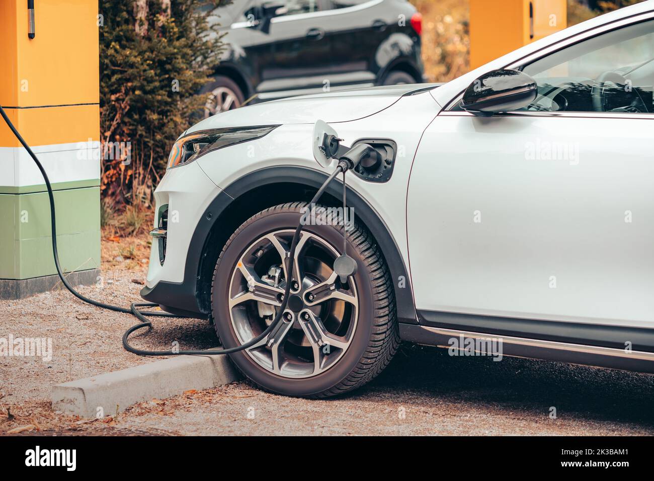 a modern electric car is charged in the parking lot. Environmental ...