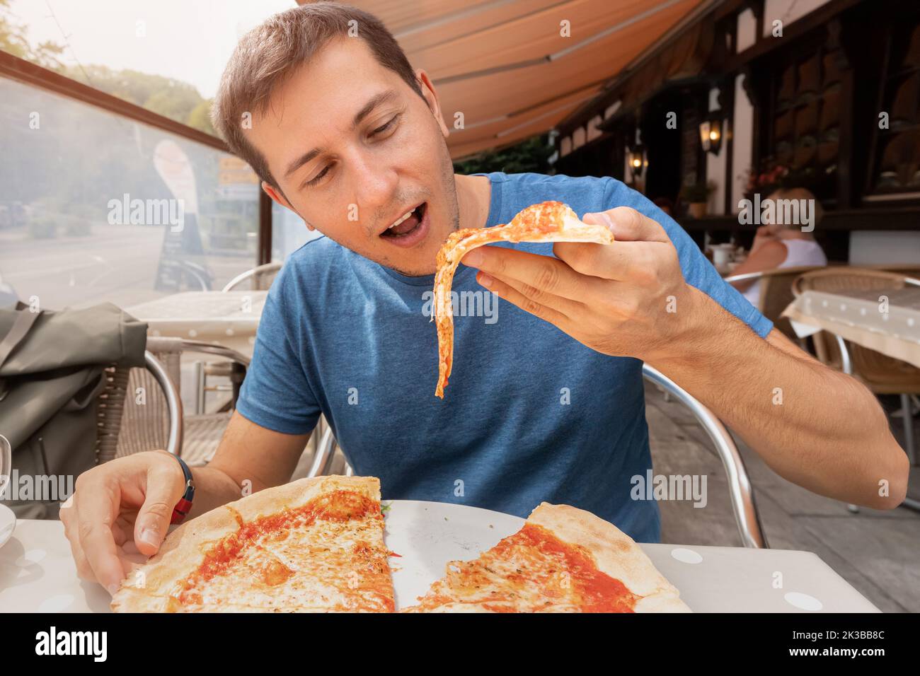 Happy young man eating delicious margarita freshly baked and hot pizza ...