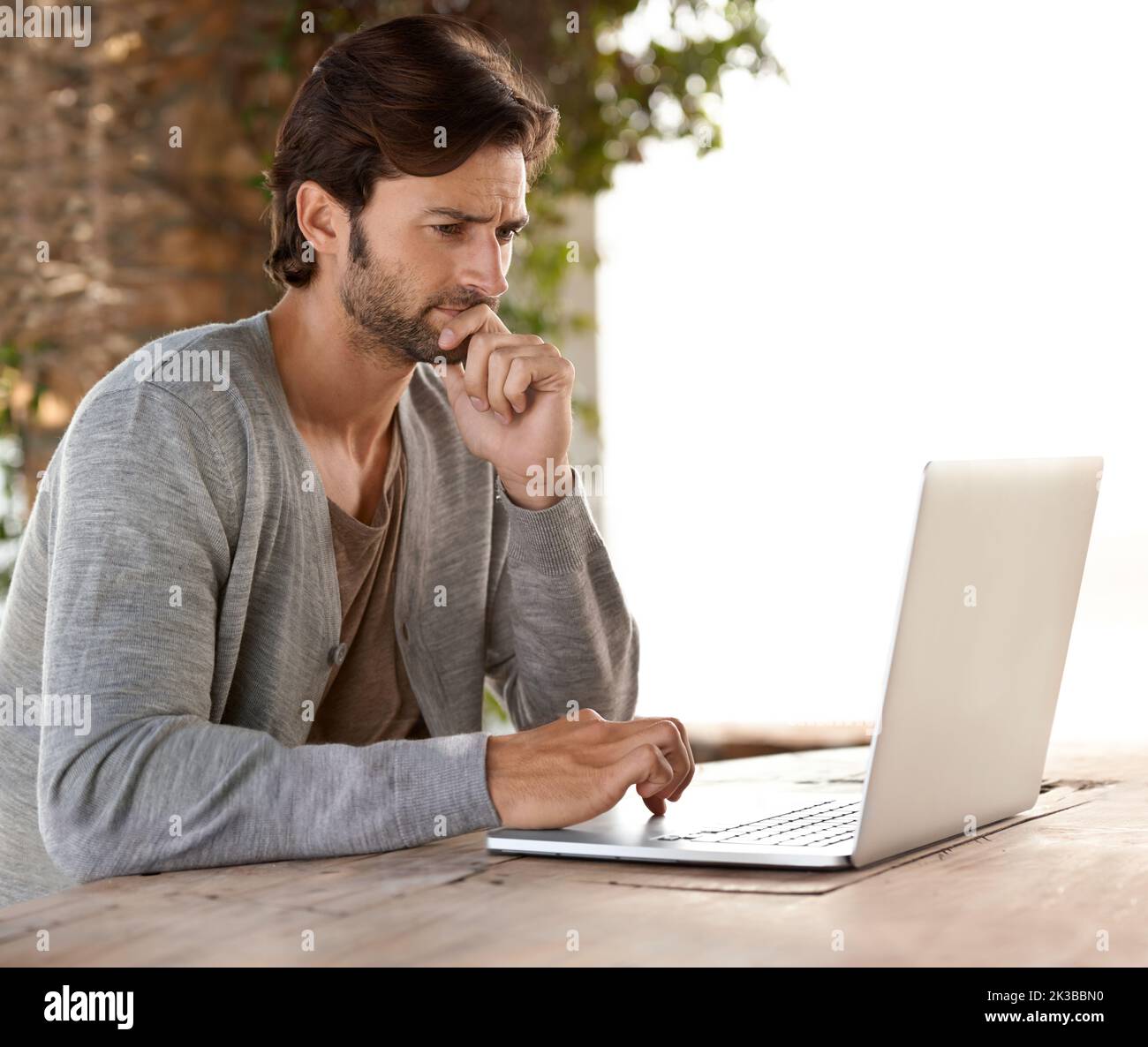 Keeping up with his work online. A handsome young man working on his ...