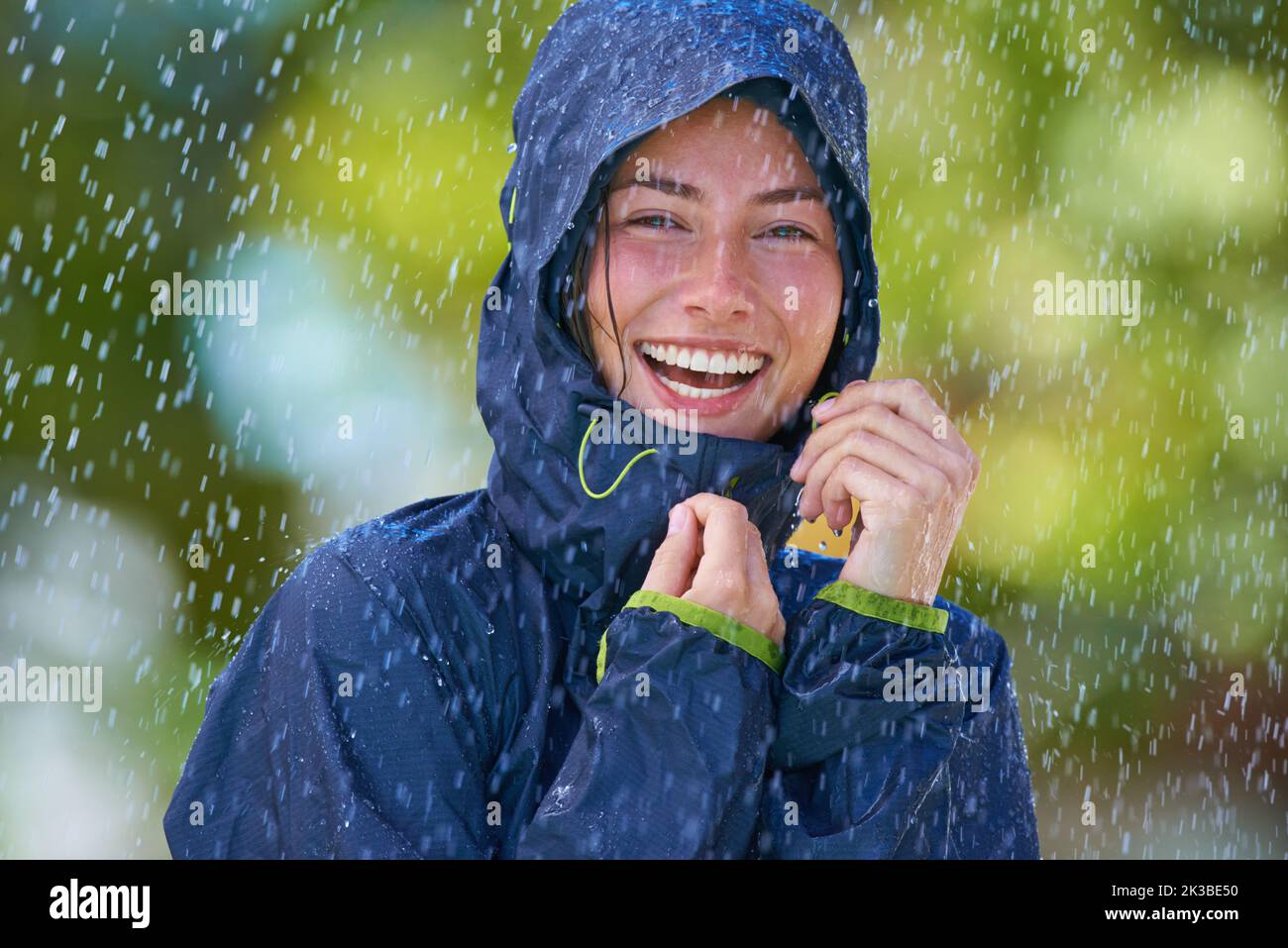 A little rain never hurt anybody. a young woman standing happily in the ...