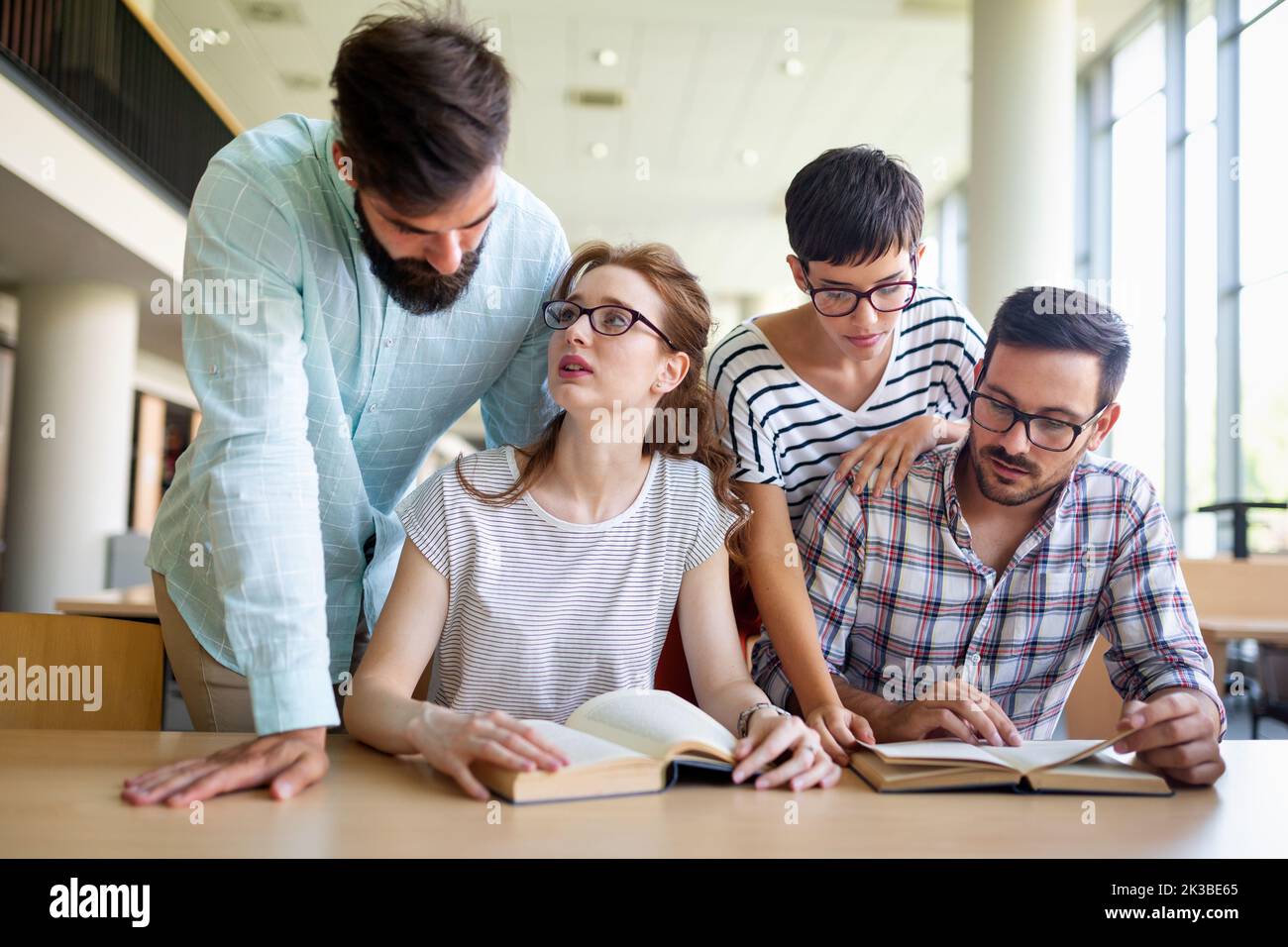 Happy university students studying with books in library. Group of ...
