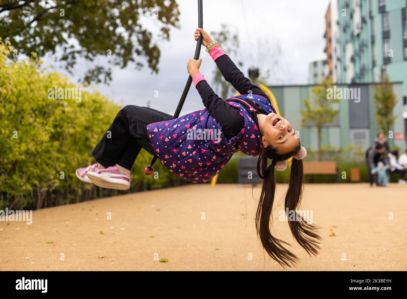 Little girl rides on Flying Fox play equipment. Child girl is smiling ...