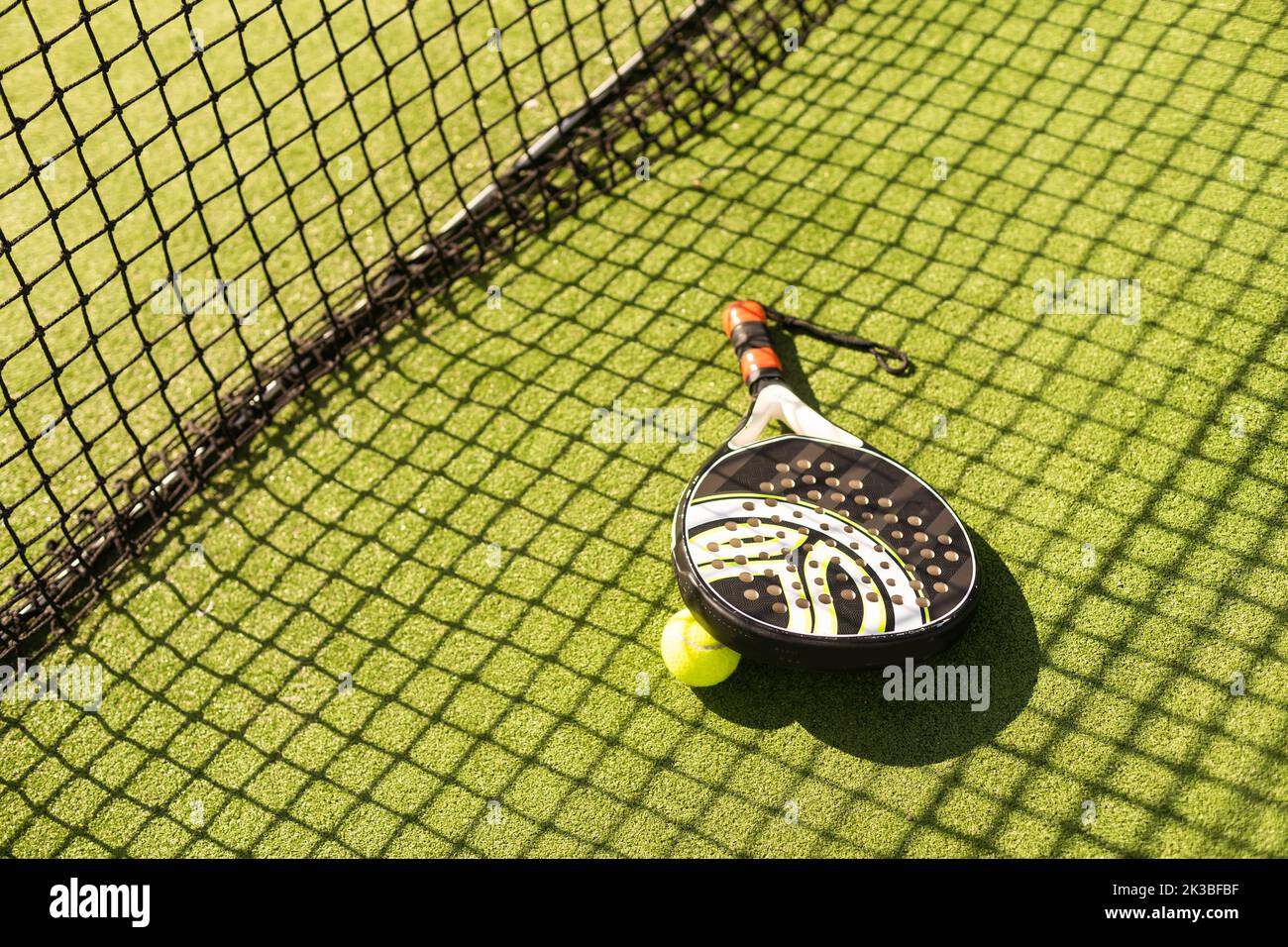 Yellow balls on grass turf near padel tennis racket behind net in green ...