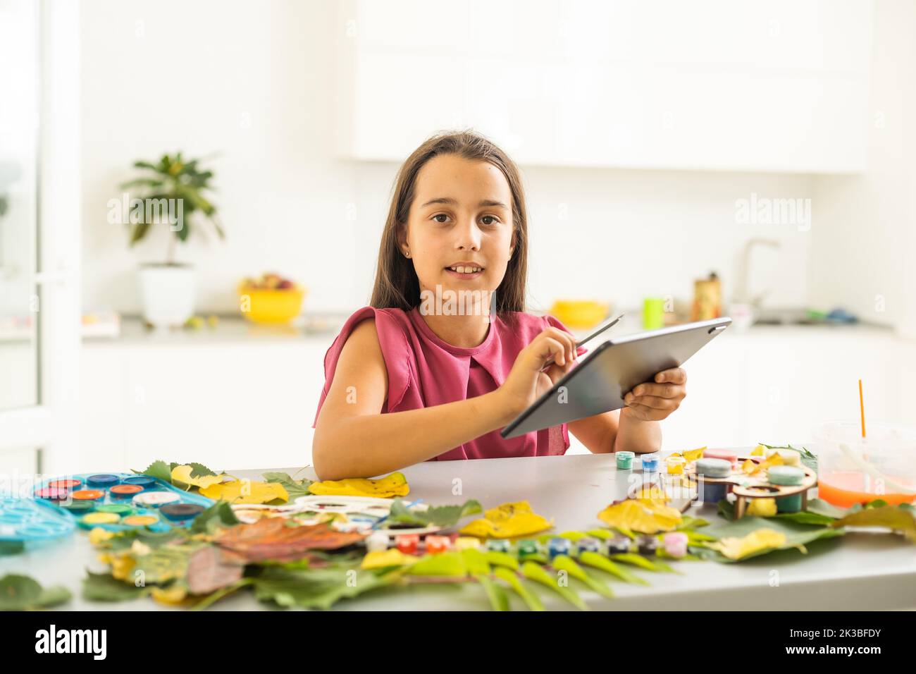 A child paints a picture of an autumn leaf with paints. Children's ...