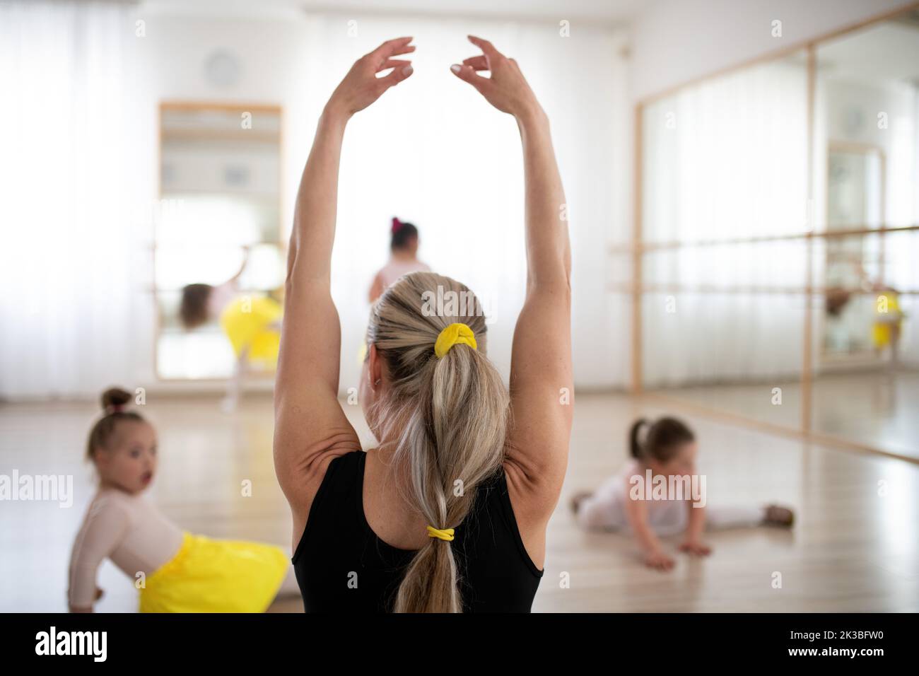 Lecteur in ballet dance studio doing stretching with little disabled ...