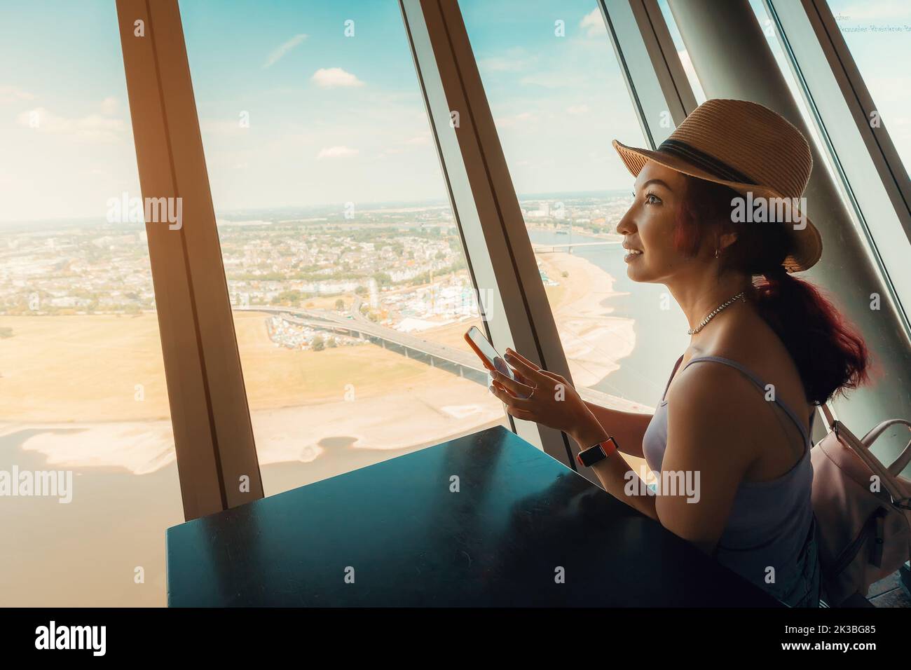 Happy girl looks and admires out of the window on the observation deck of the TV Tower in ...