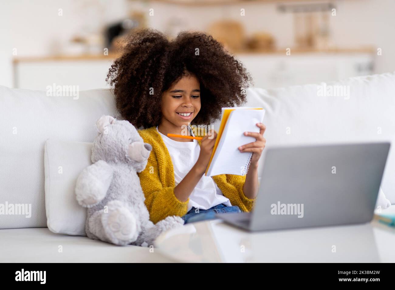 Happy black girl doing homework, using computer Stock Photo - Alamy