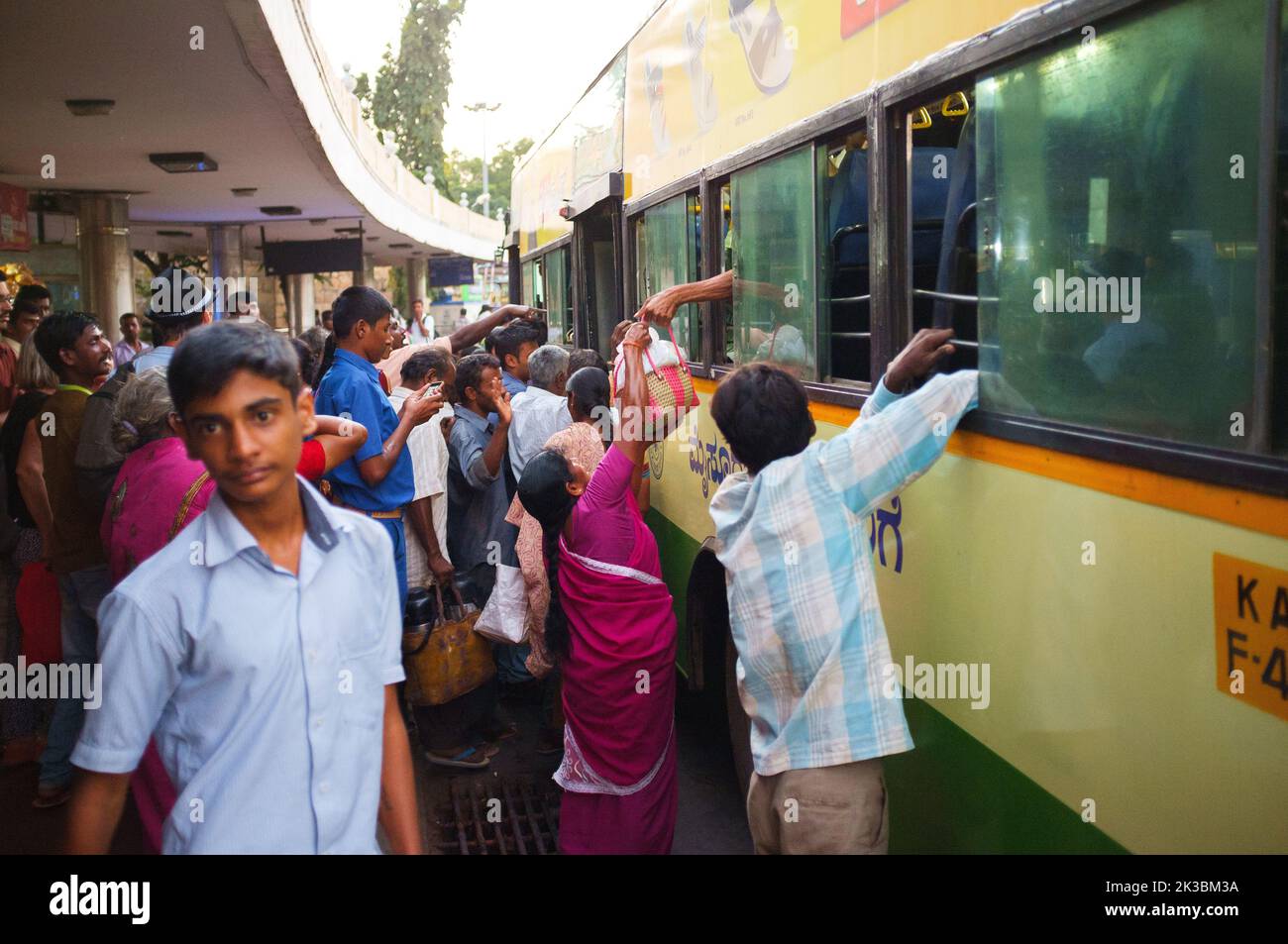 A group of people trying to get on the bus in a station in Mysore ...