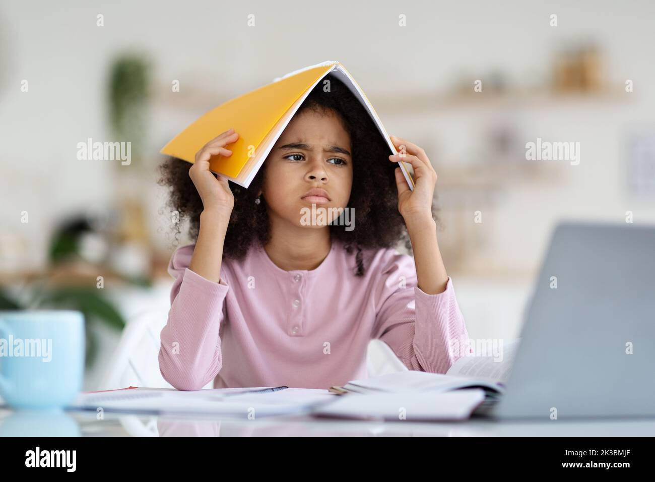 Angry black girl schooler doing homework at home Stock Photo - Alamy