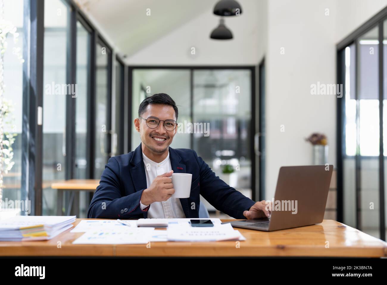 Portrait friendly smiling handsome asian businessman sitting and using ...