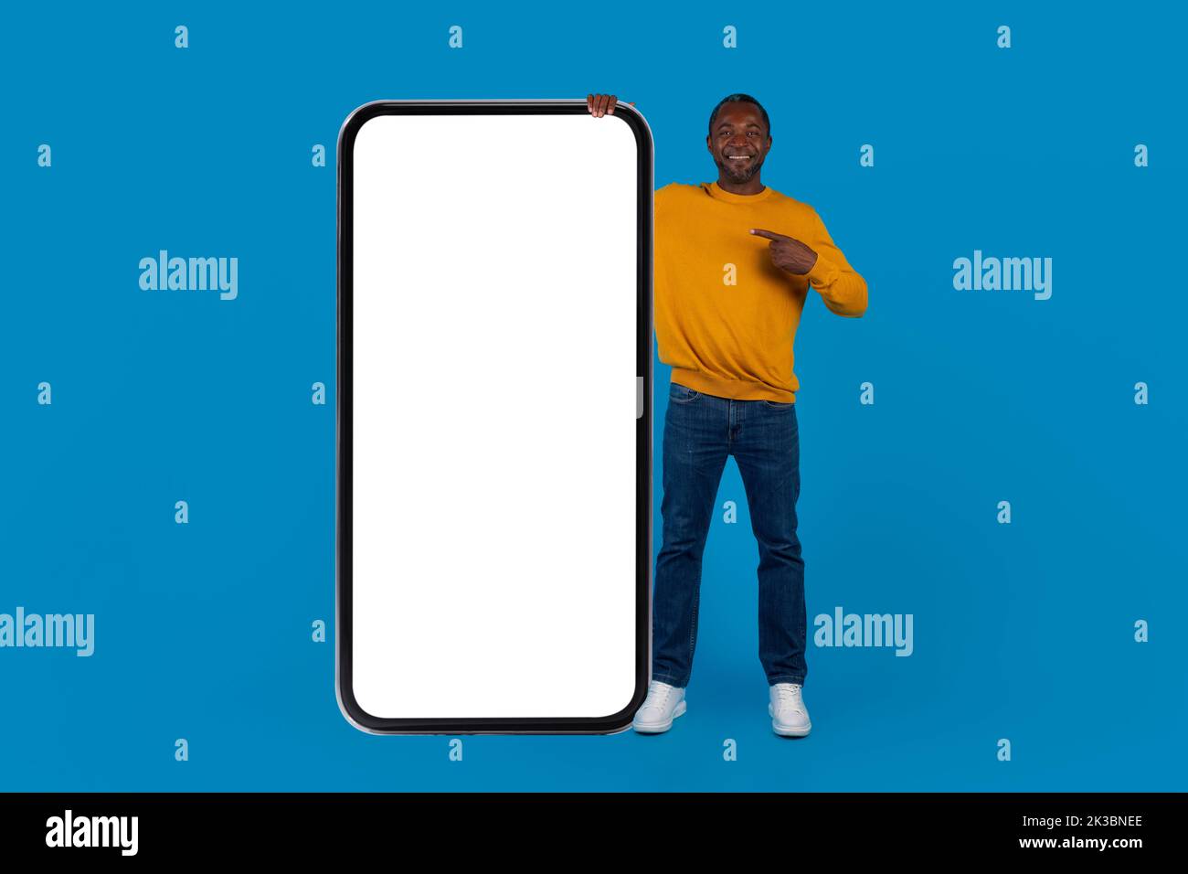 Positive black man pointing at big cell phone, mockup Stock Photo - Alamy