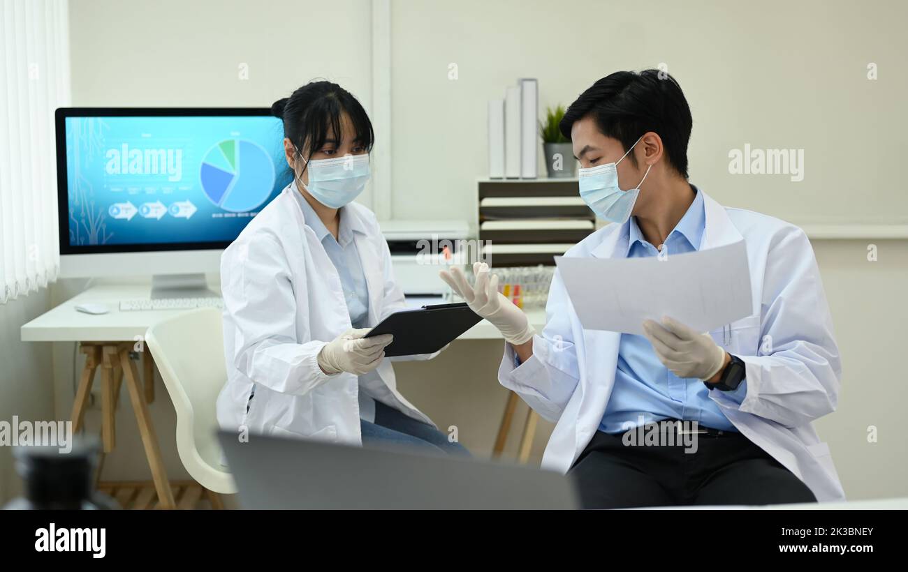 Young researcher scientist analyzing test samples, discussing about new ...