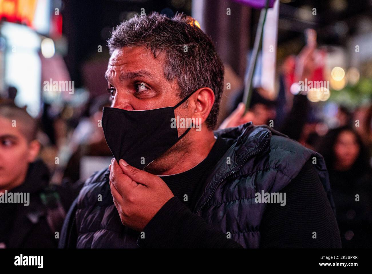 A masked protester rallies others on the streets under neon lights at ...