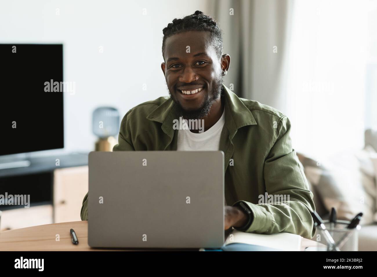Cheerful african american guy programmer sitting at workdesk at home ...
