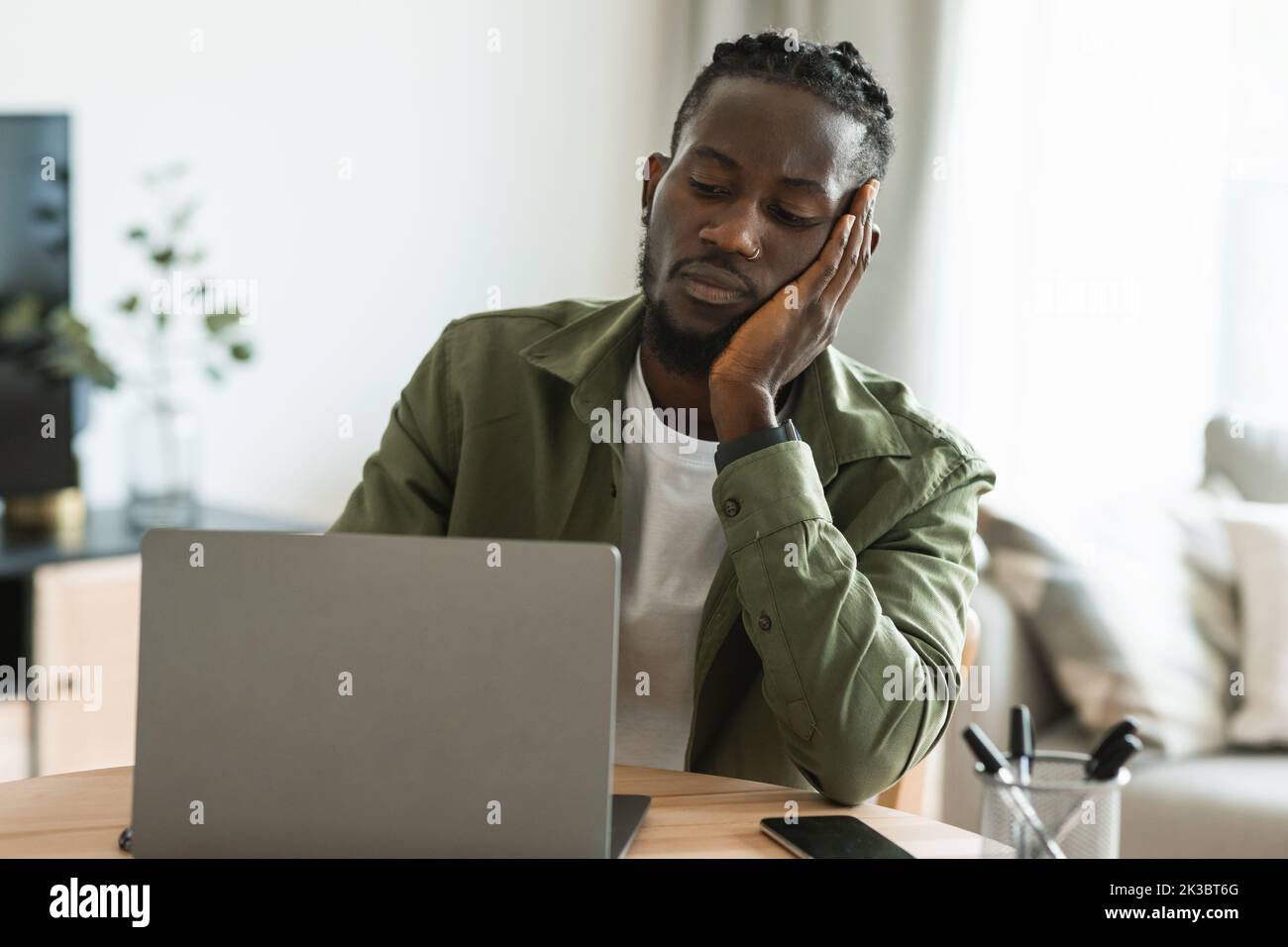 Freelance stress concept. Overworked sad black man sitting at workplace ...