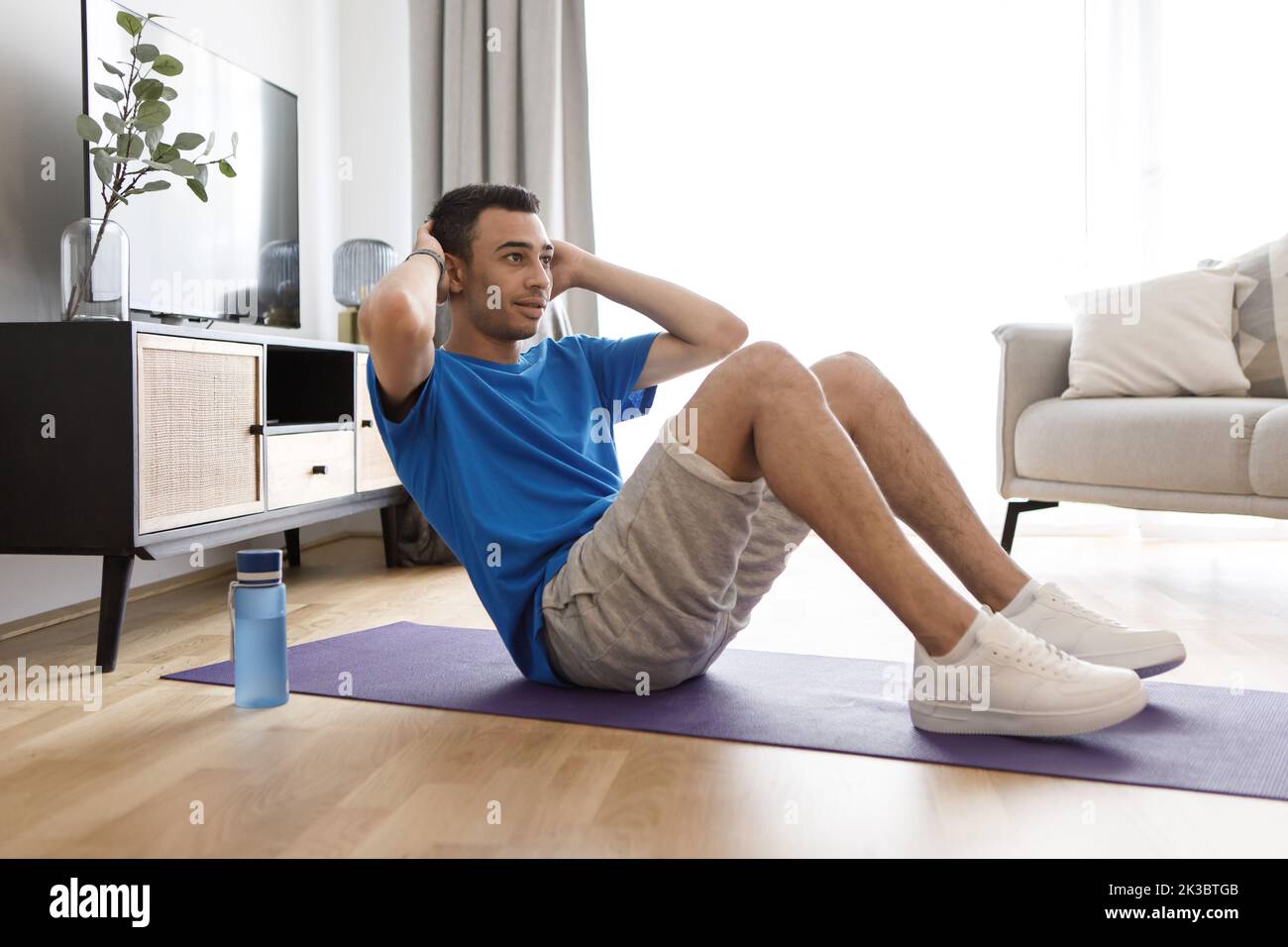 Young arab man exercising on yoga mat, strengthening abs muscles during ...