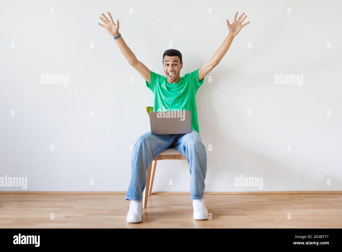 Emotional arab man sitting on chair with laptop and raising hands up ...