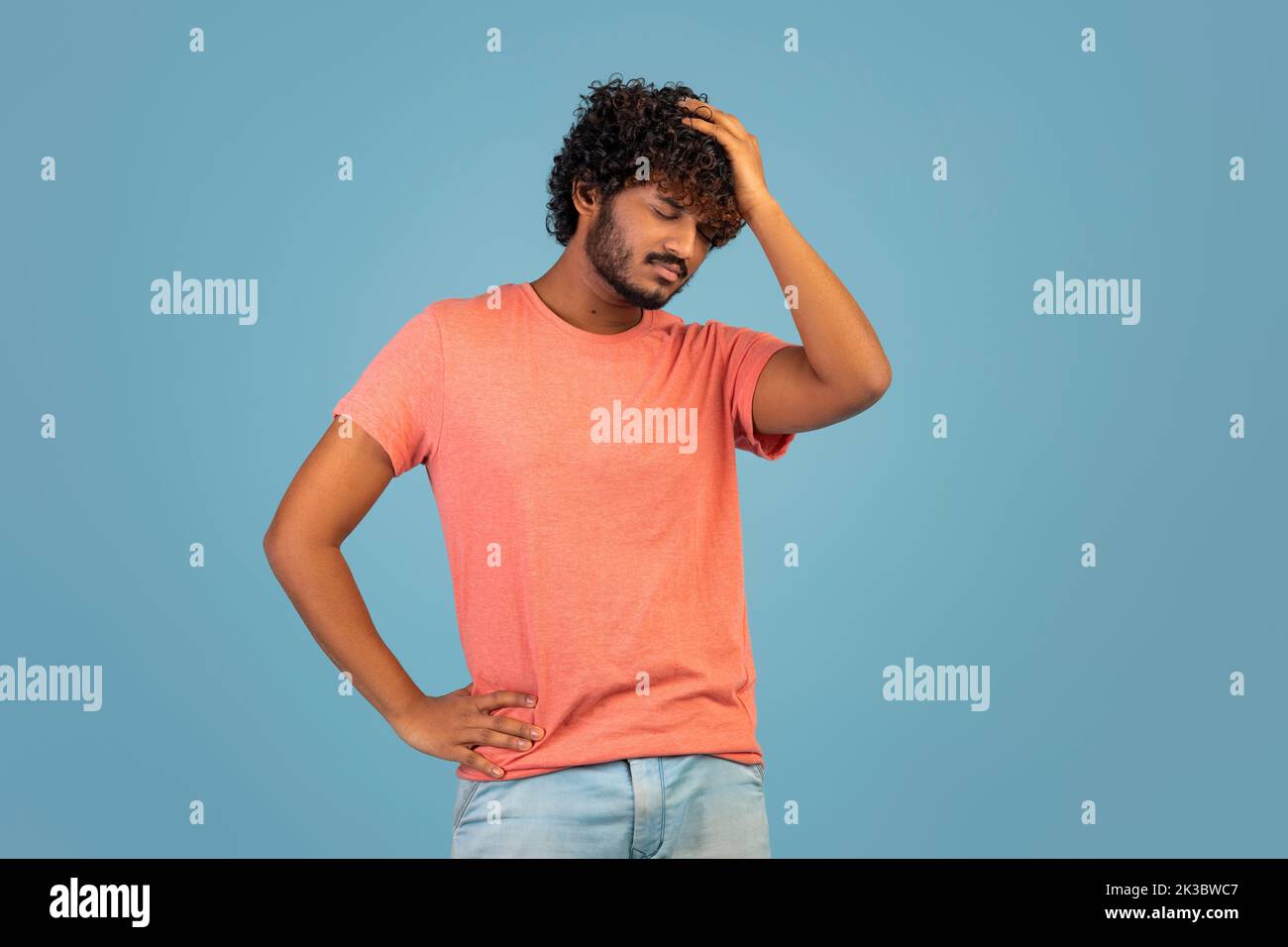 Uspet indian guy touching his head, blue background Stock Photo - Alamy