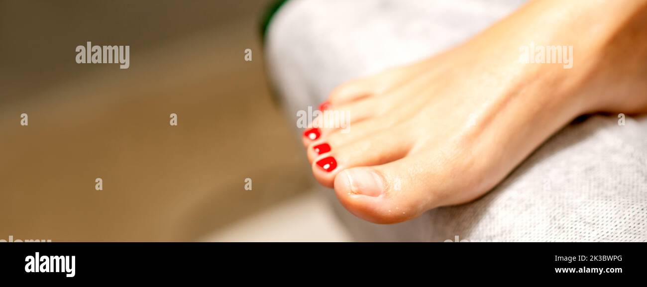 Nail painting process. Red painted fingernails on a female leg in a ...