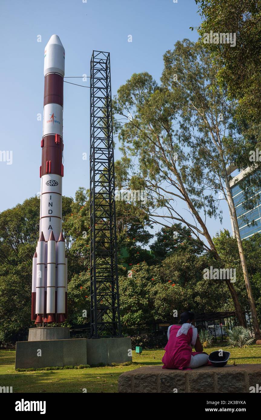 A vertical shot of a woman sitting next to a space rocket tower model ...