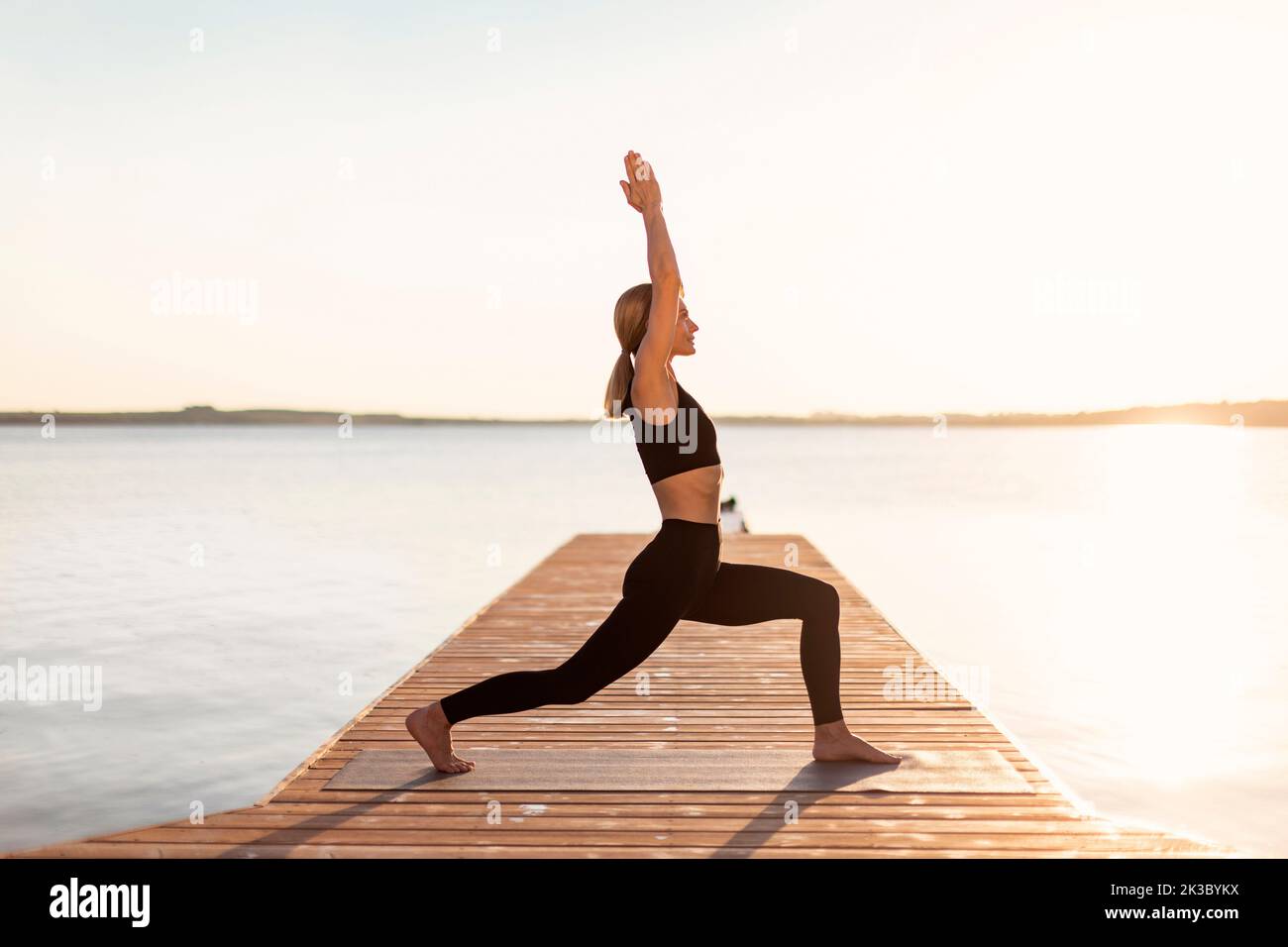 Slim Middle Aged Woman Practicing Yoga Outdoors, Making Warrior 1 Pose Stock Photo - Alamy