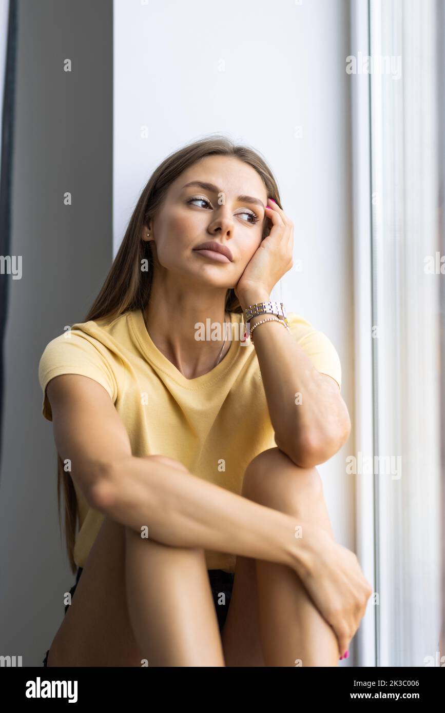 Sad depressed woman having social problems sitting on windowsill Stock ...