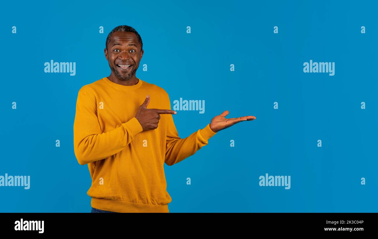 Happy black man showing something on his hand Stock Photo - Alamy