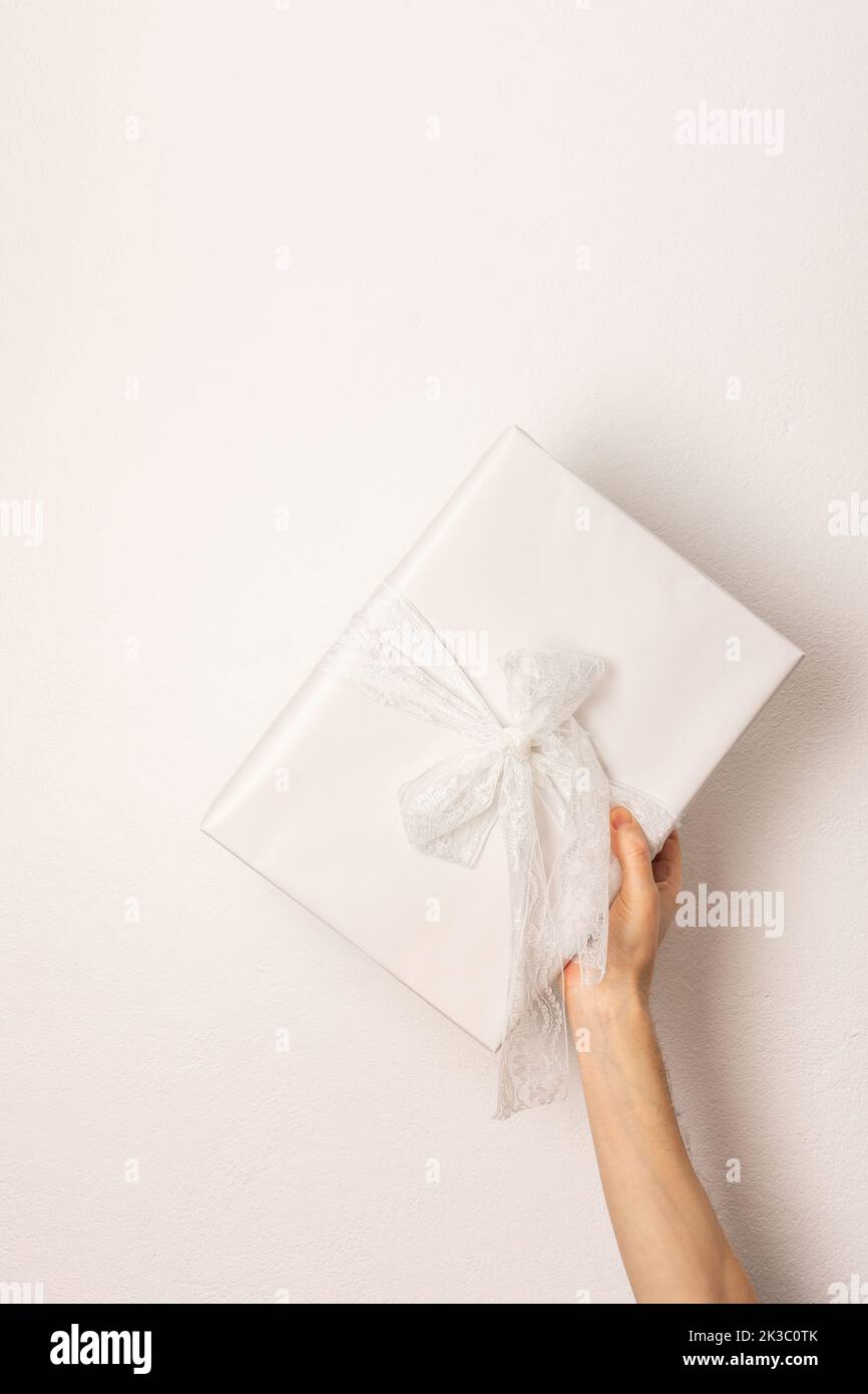 Man's hand holding a white gift box with a bow, Merry Christmas and ...