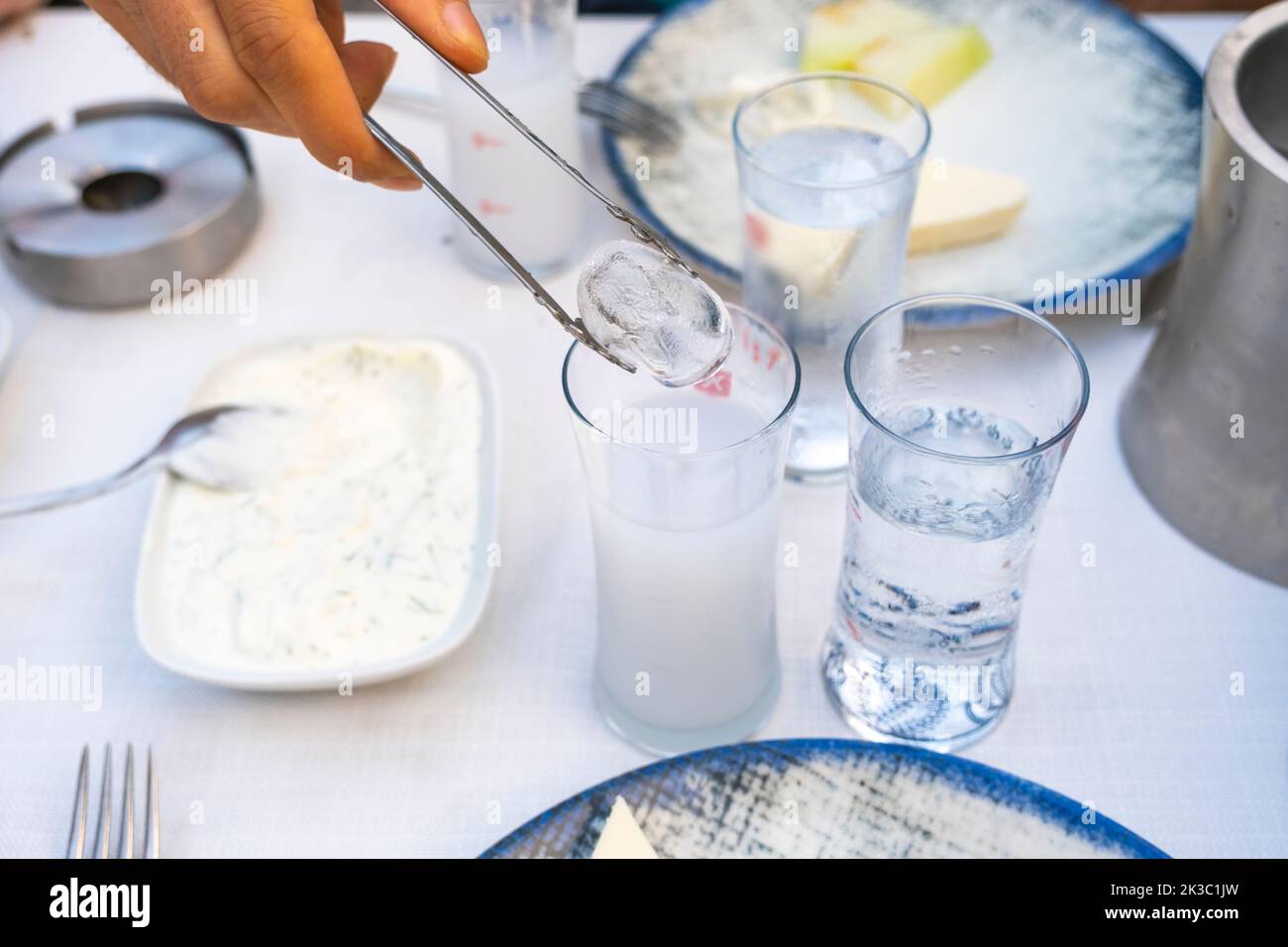 Man hand putting ice cube into Raki glass, traditional Turkish alcohol ...