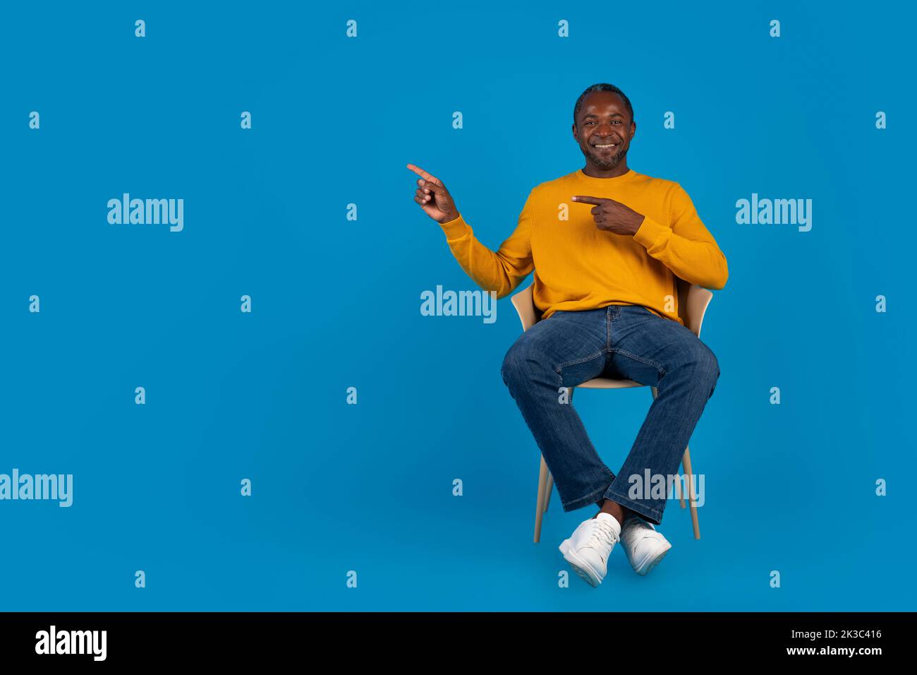 Relaxed black man sitting on chair, showing copy space Stock Photo - Alamy