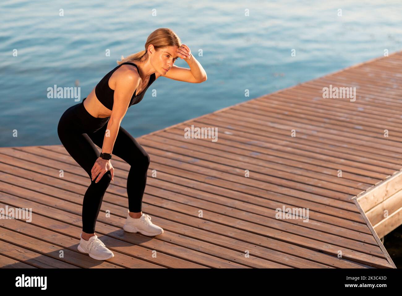 Tired Middle Aged Female Jogger Resting After Run On Pier Near River ...
