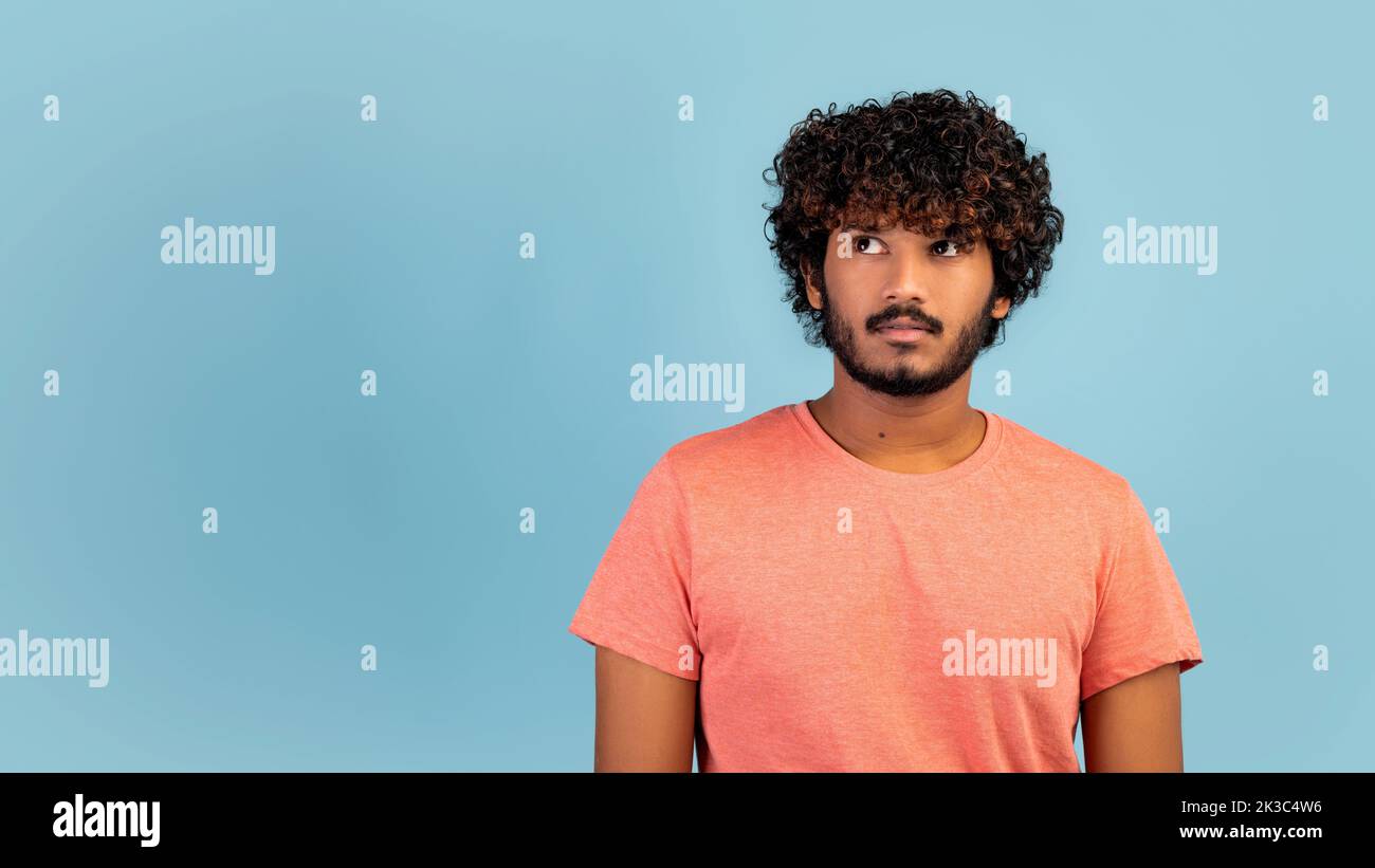 Curious indian guy looking at copy space over blue background Stock ...