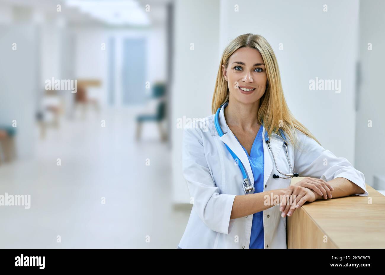 Beautiful female general practitioner with stethoscope standing in ...