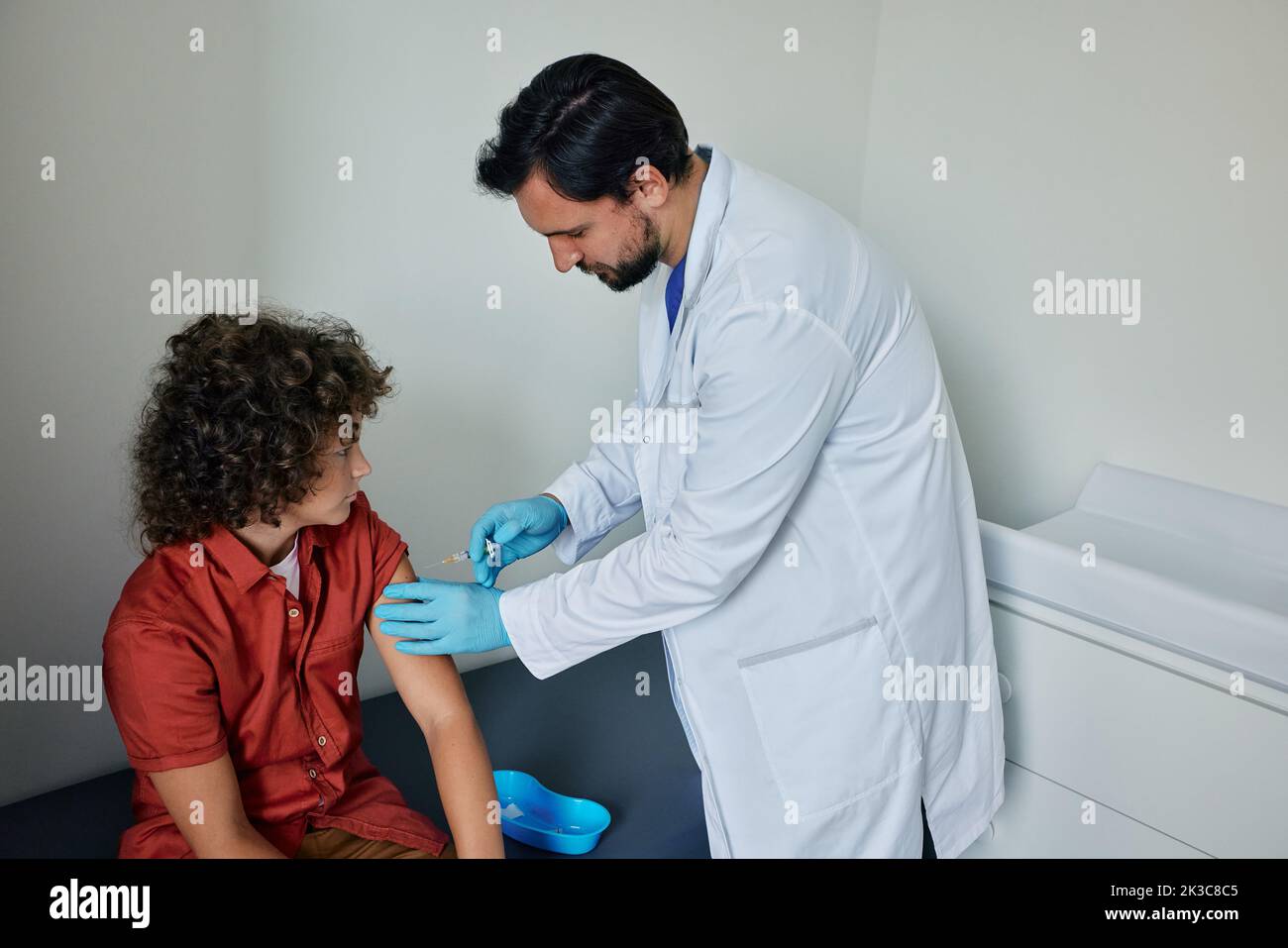 Teenage boy during vaccinated by general practitioner in doctor's ...