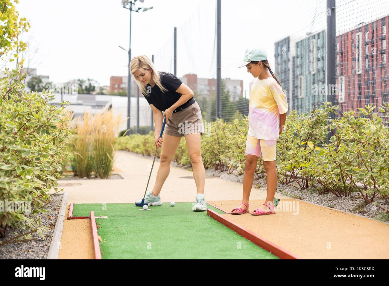 Detail of young woman and daughter playing mini adventure golf on a ...