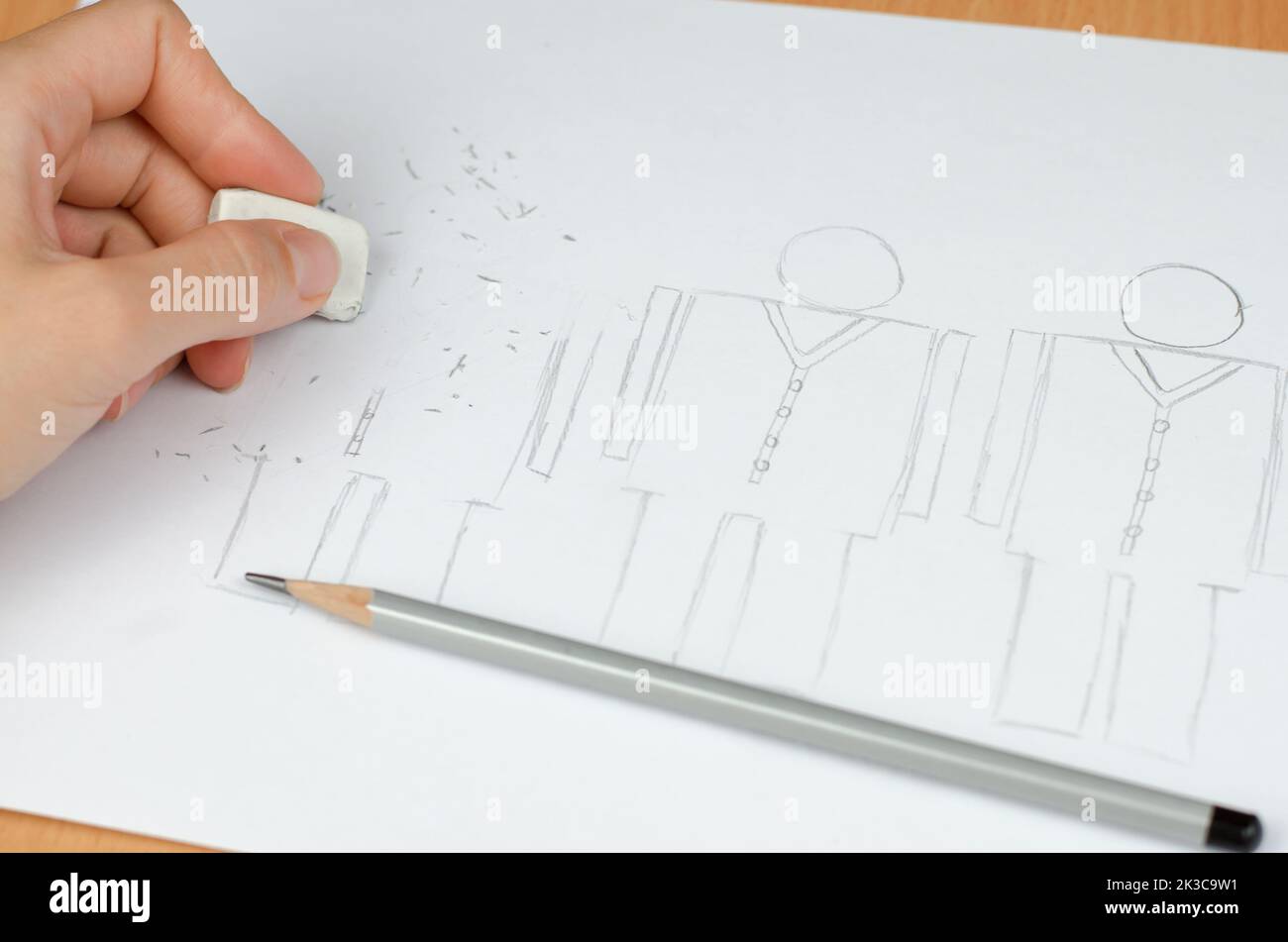 Women's hands wipe a person drawn with a pencil with an eraser. The ...