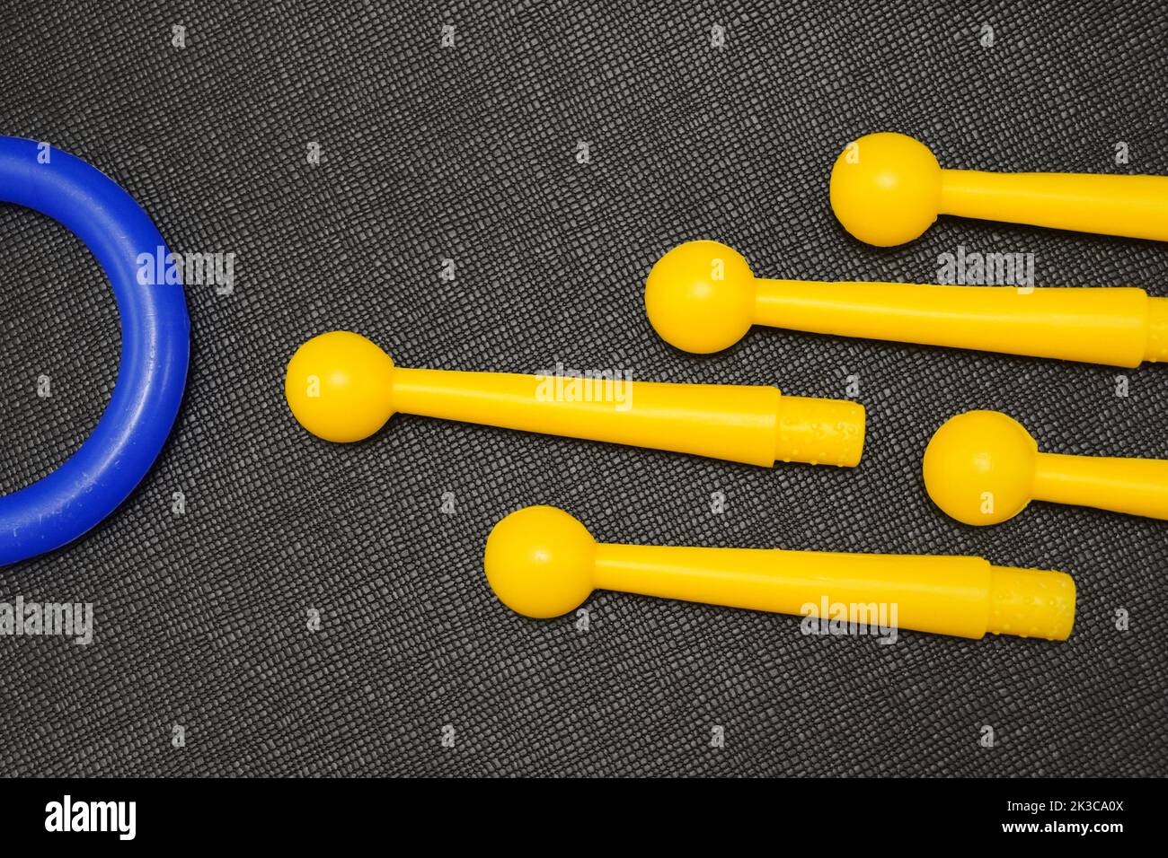 Concept with yellow and blue toy sticks and rings in front of black ...