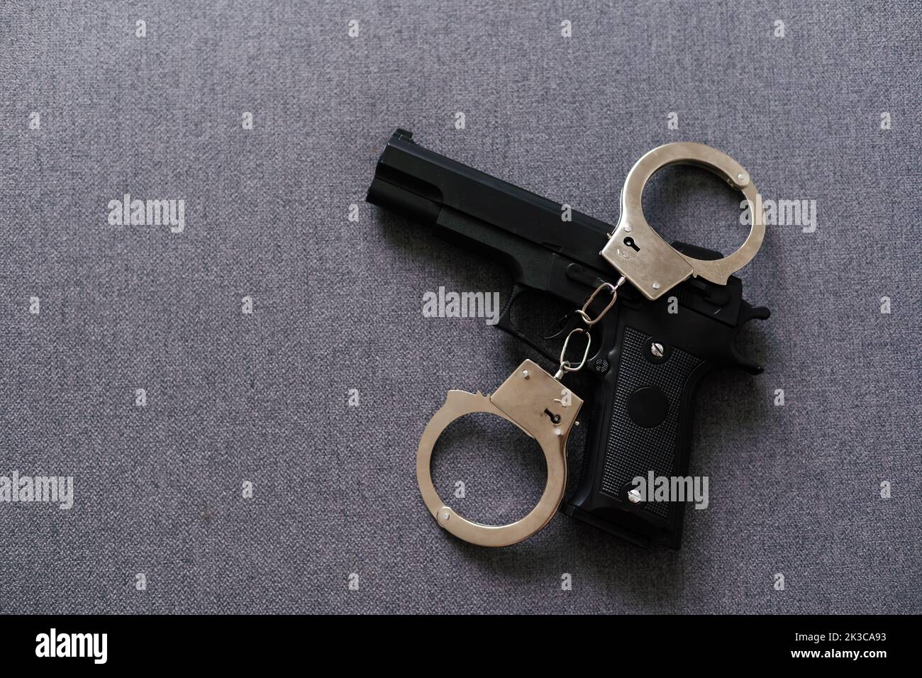 Black gun and metal handcuffs lie on the black background. Private ...