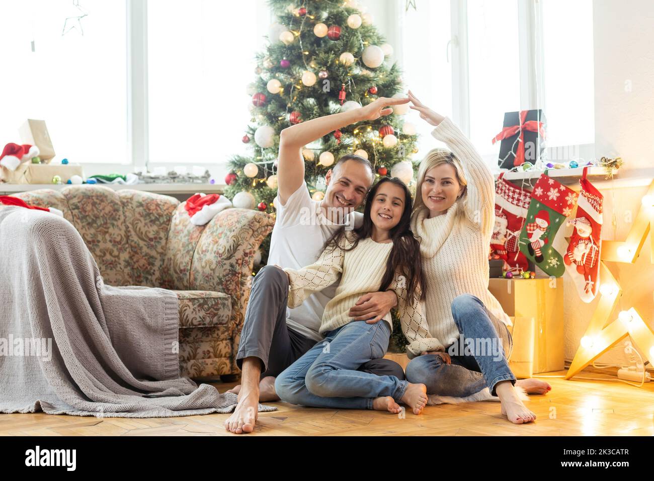Beautiful young family enjoying their holiday time together, decorating ...