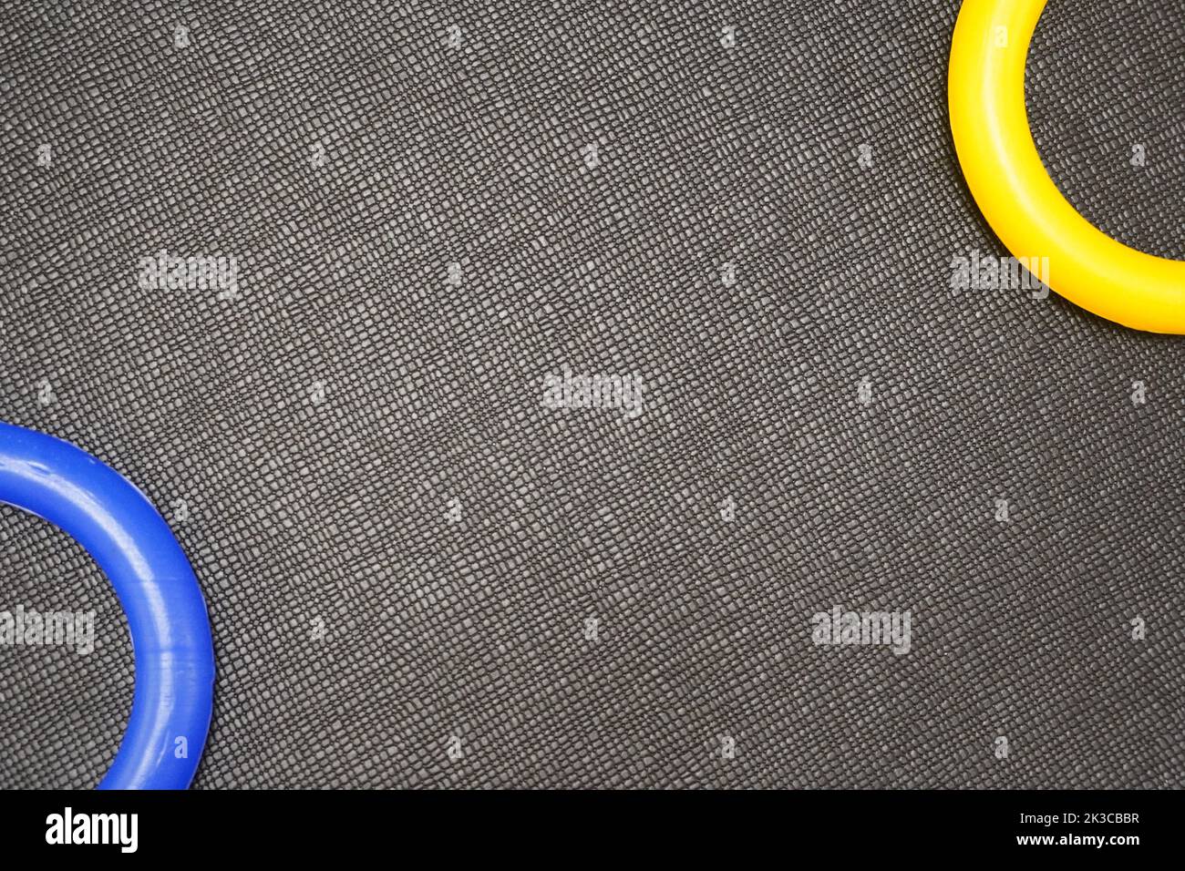 Concept with yellow and blue toy rings in front of black background ...