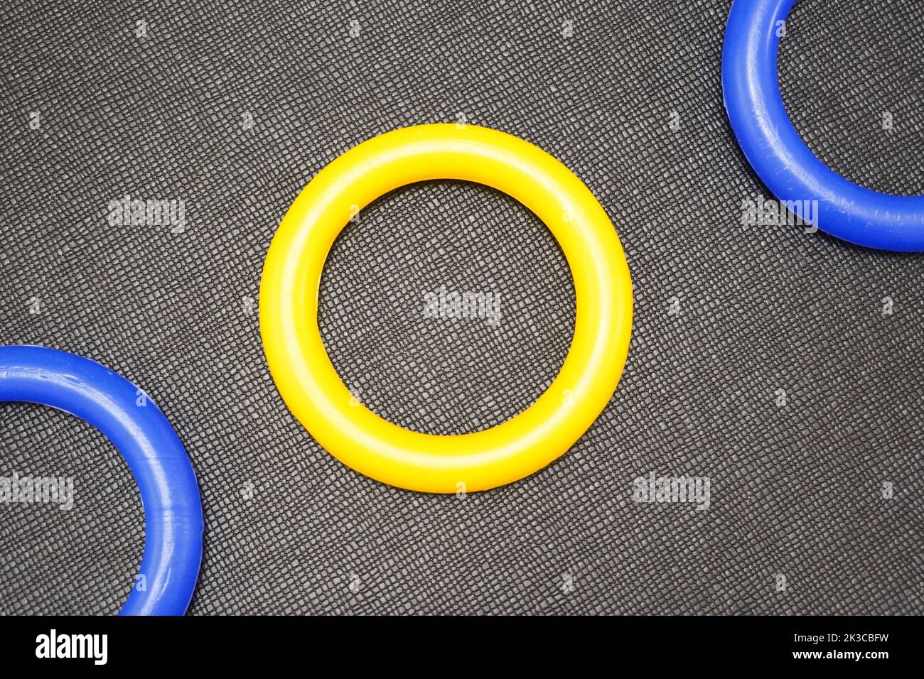 Concept with yellow and blue toy rings in front of black background ...
