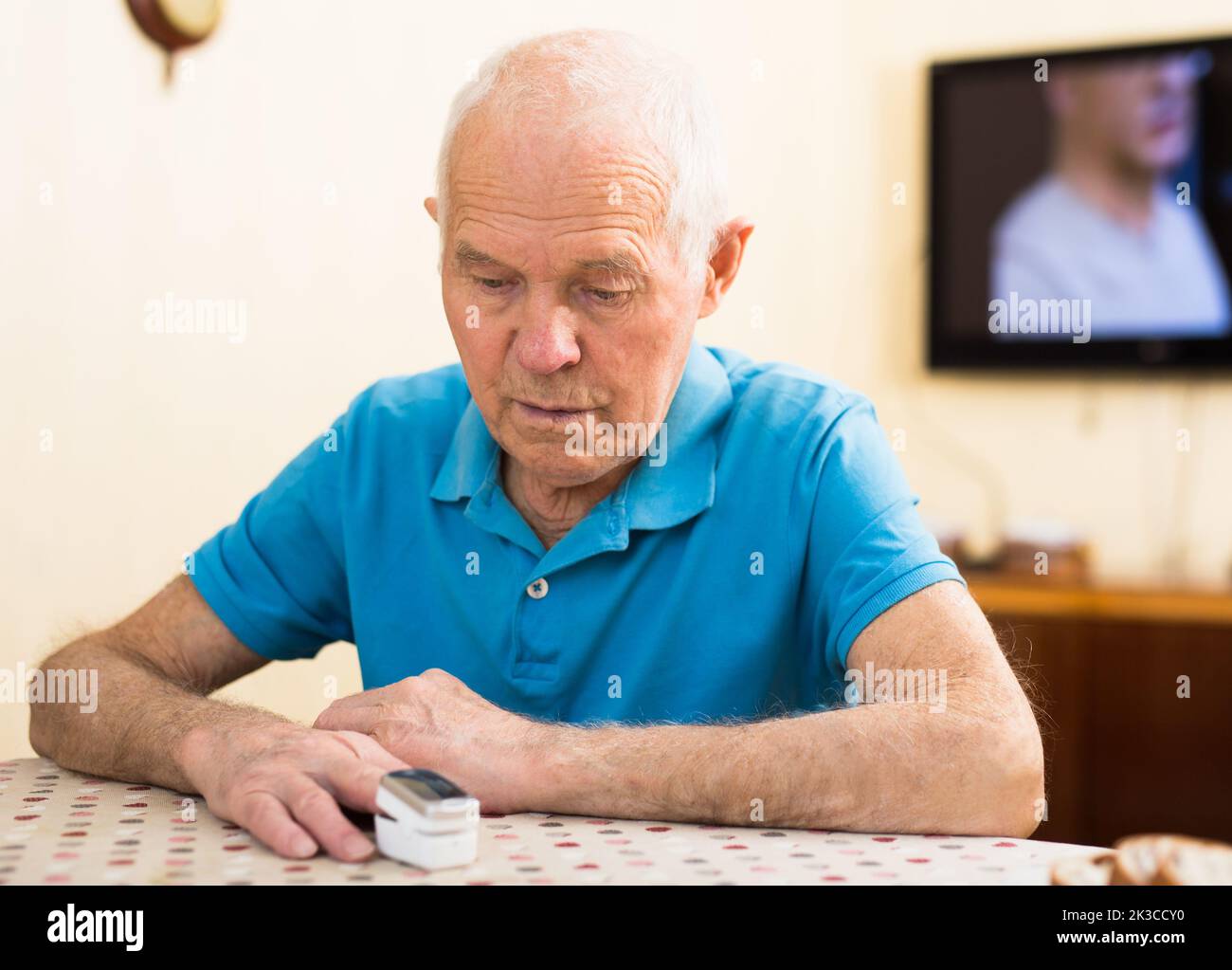 Focused worried elderly man measuring himself oxygen saturation while ...