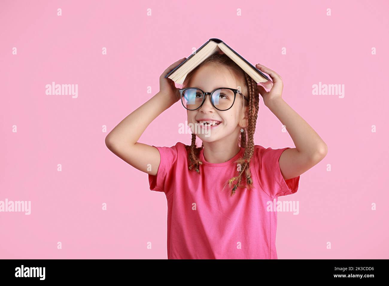 Back to school concept. Smiling pretty little school girl in glasses is ...