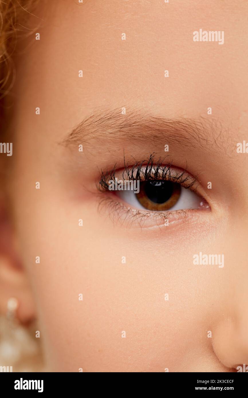 Closeup of little girl's eye with black curly eyelashes. Kids ...