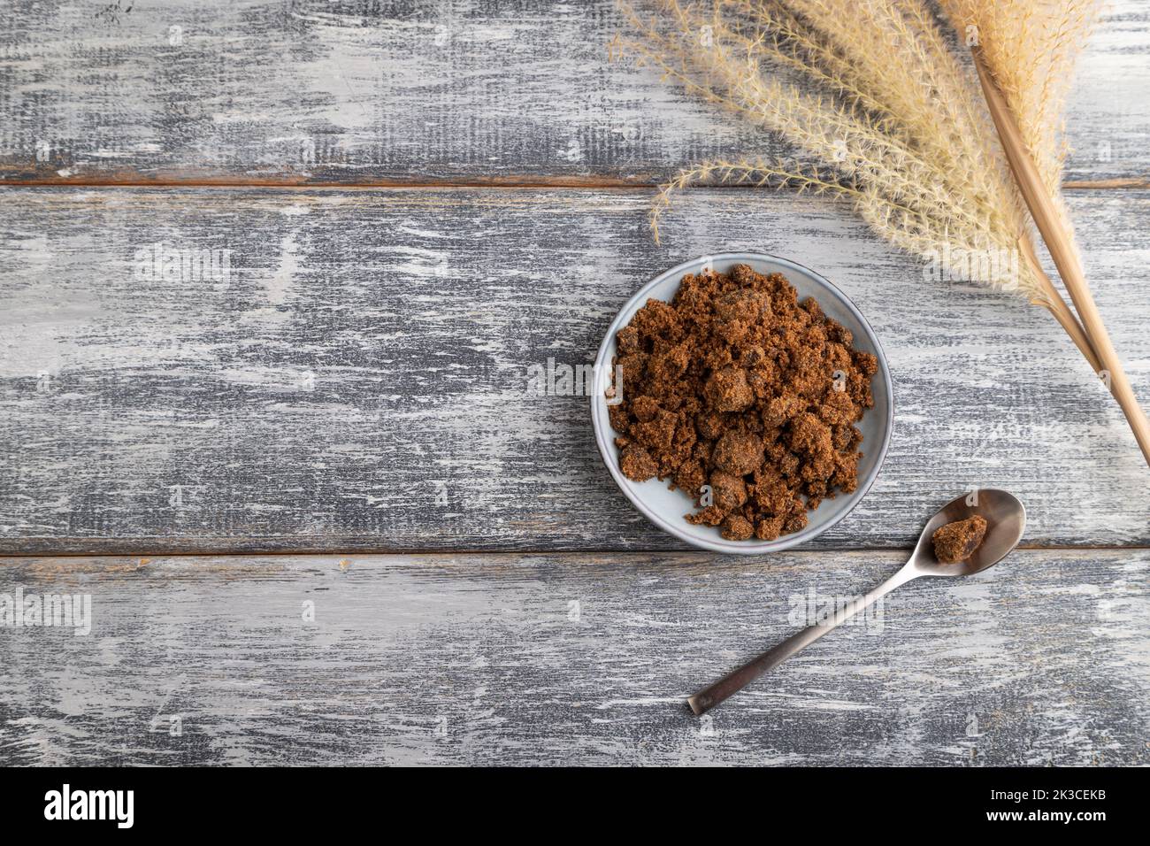 plate with unrefined brown cane sugar on gray wooden background. top ...