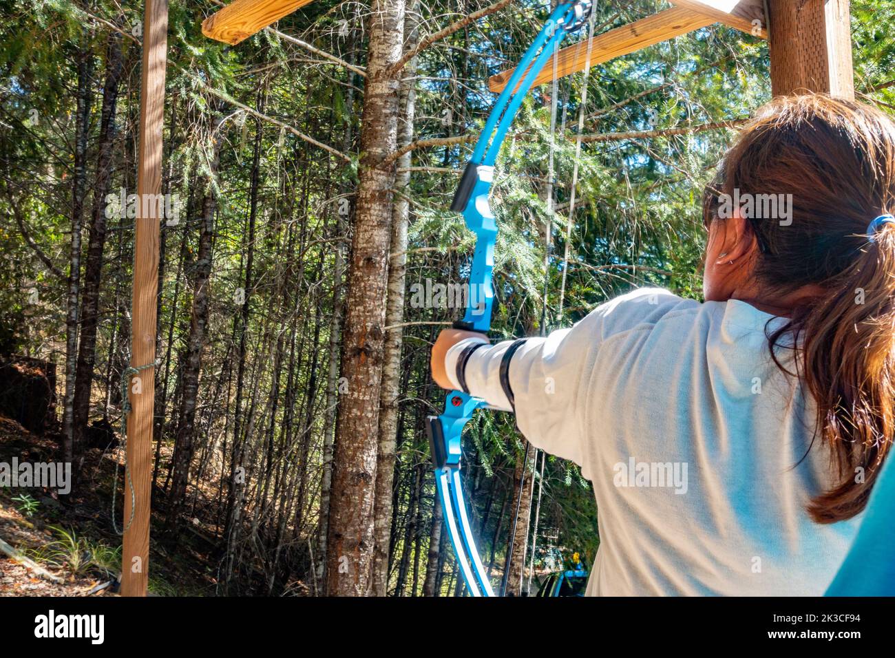 A lady having a go at archery, bow drawn and aimed Stock Photo - Alamy