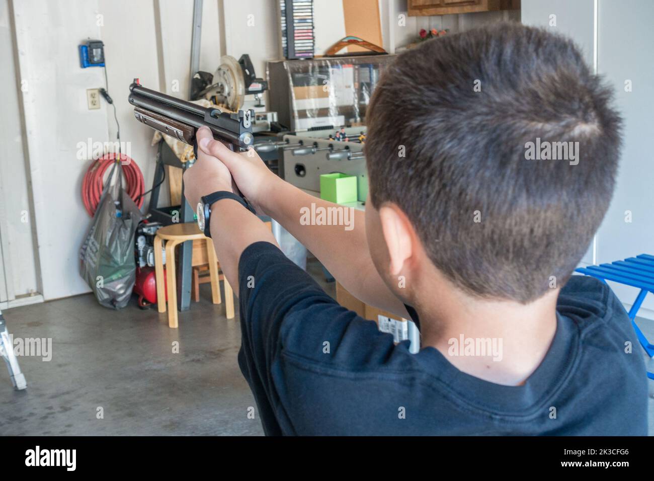 Over the shoulder view of a boy aiming and shooting an air pistol in a ...