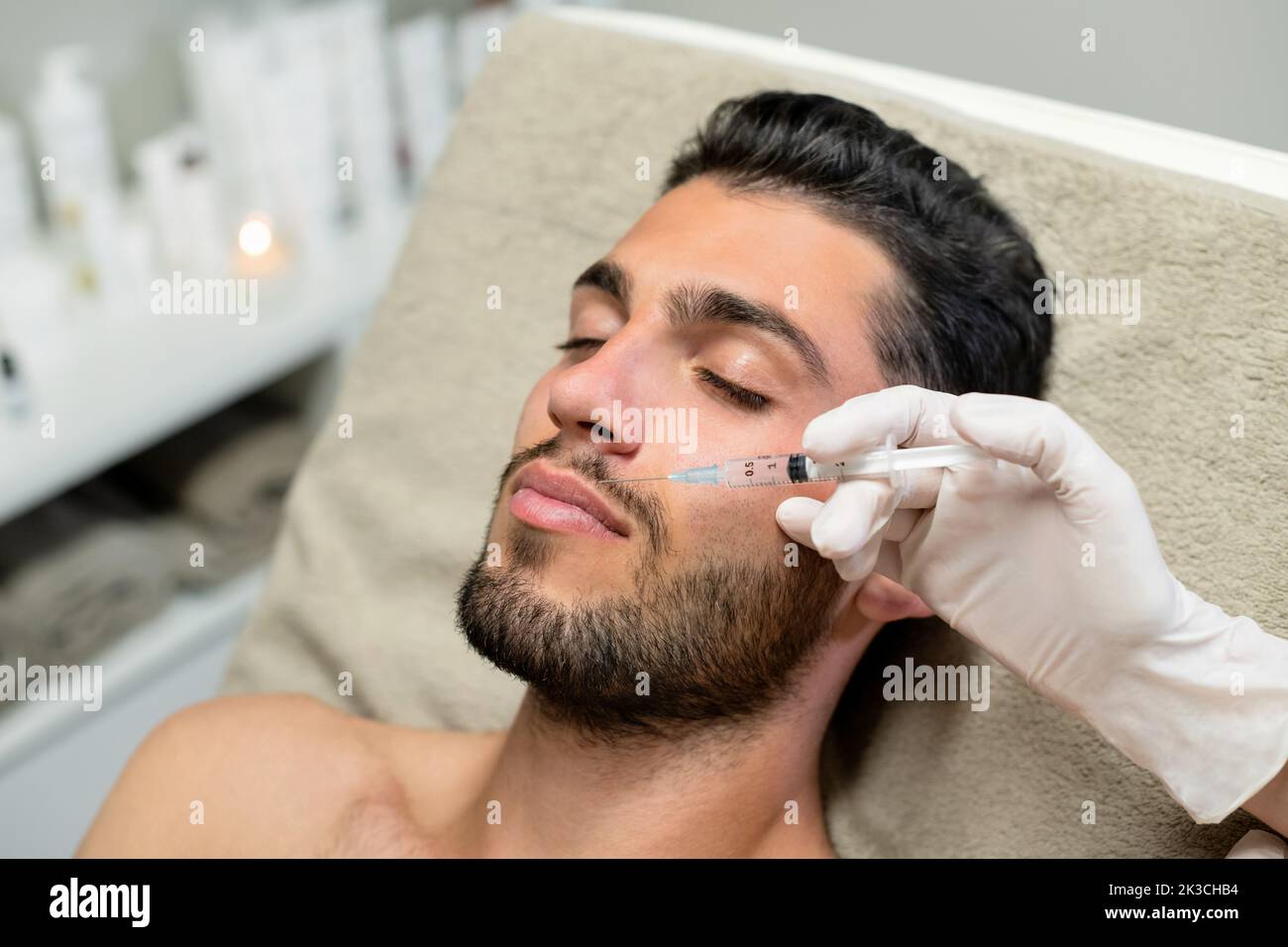 From above cosmetician in white glove using syringe to inject ...